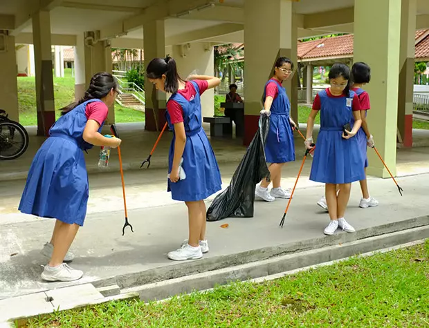 Học sinh của trường cho các cô gái đang vật nuôi đang vật lộn với rác